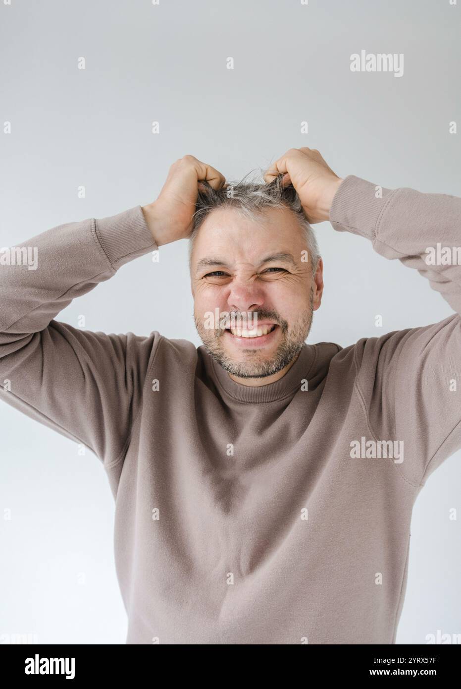 Close-up portrait of a man pulling at his hair in frustration or anger ...
