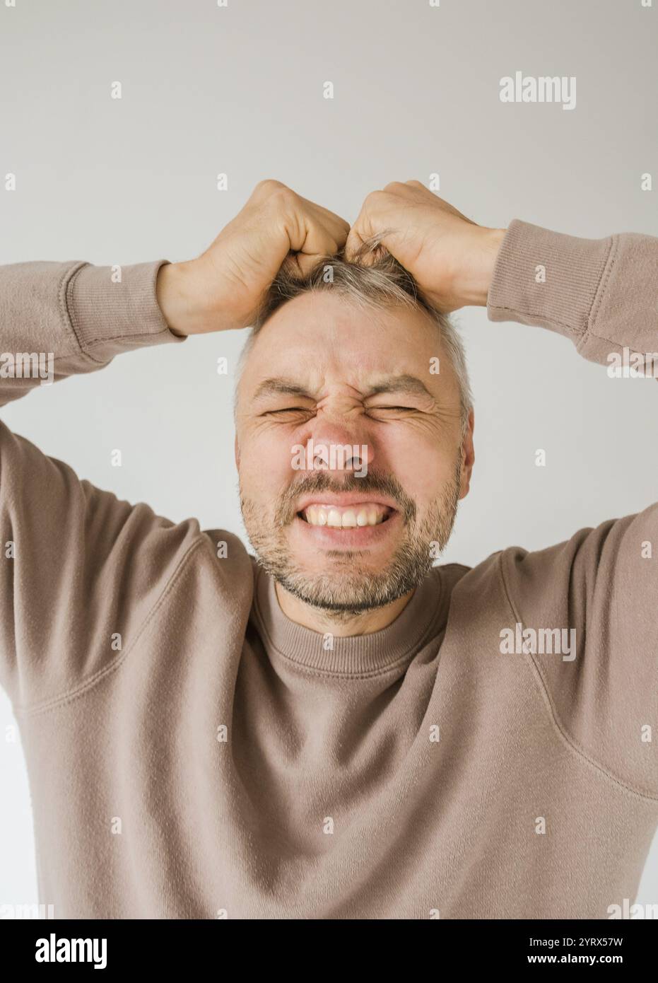 Close-up portrait of a man clutching his hair in frustration or anger ...