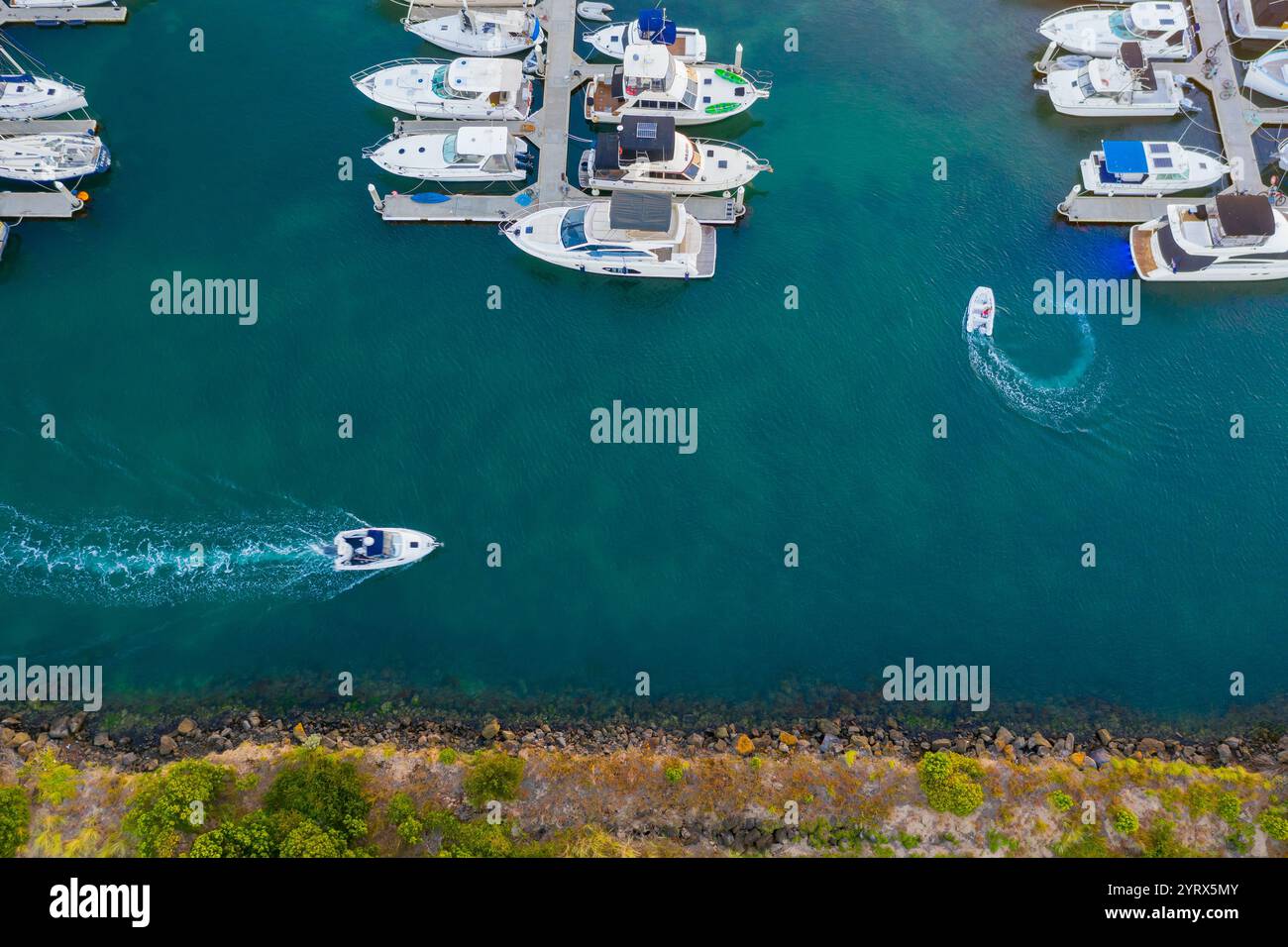 A small boat entering a coastal marina full of boats at anchor at ...