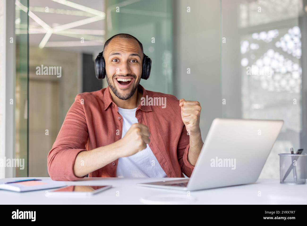 Young man enthusiastically cheers in office, celebrating success. He ...