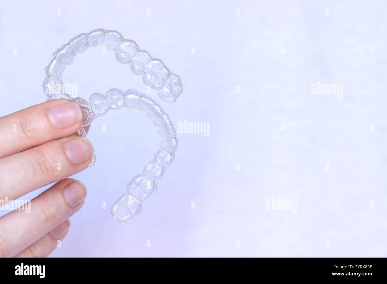 Hand holding Invisalign transparent braces on white background with ...