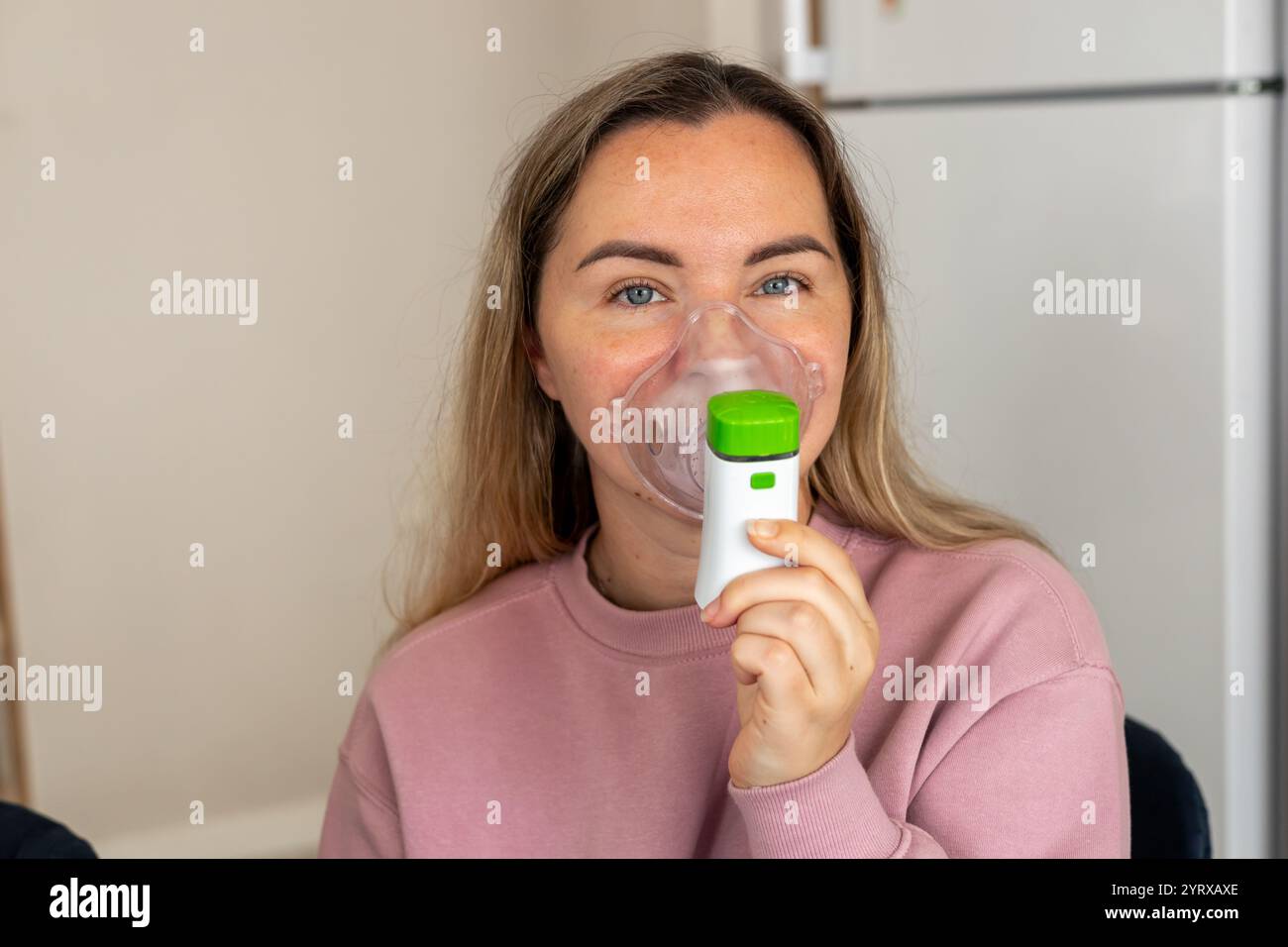 Woman using a nebulizer at home for respiratory therapy in a cozy ...