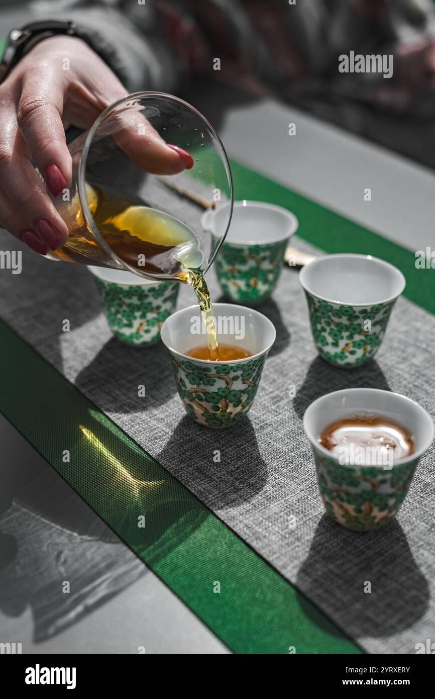 Pouring tea into beautifully crafted traditional cups with elegant ...