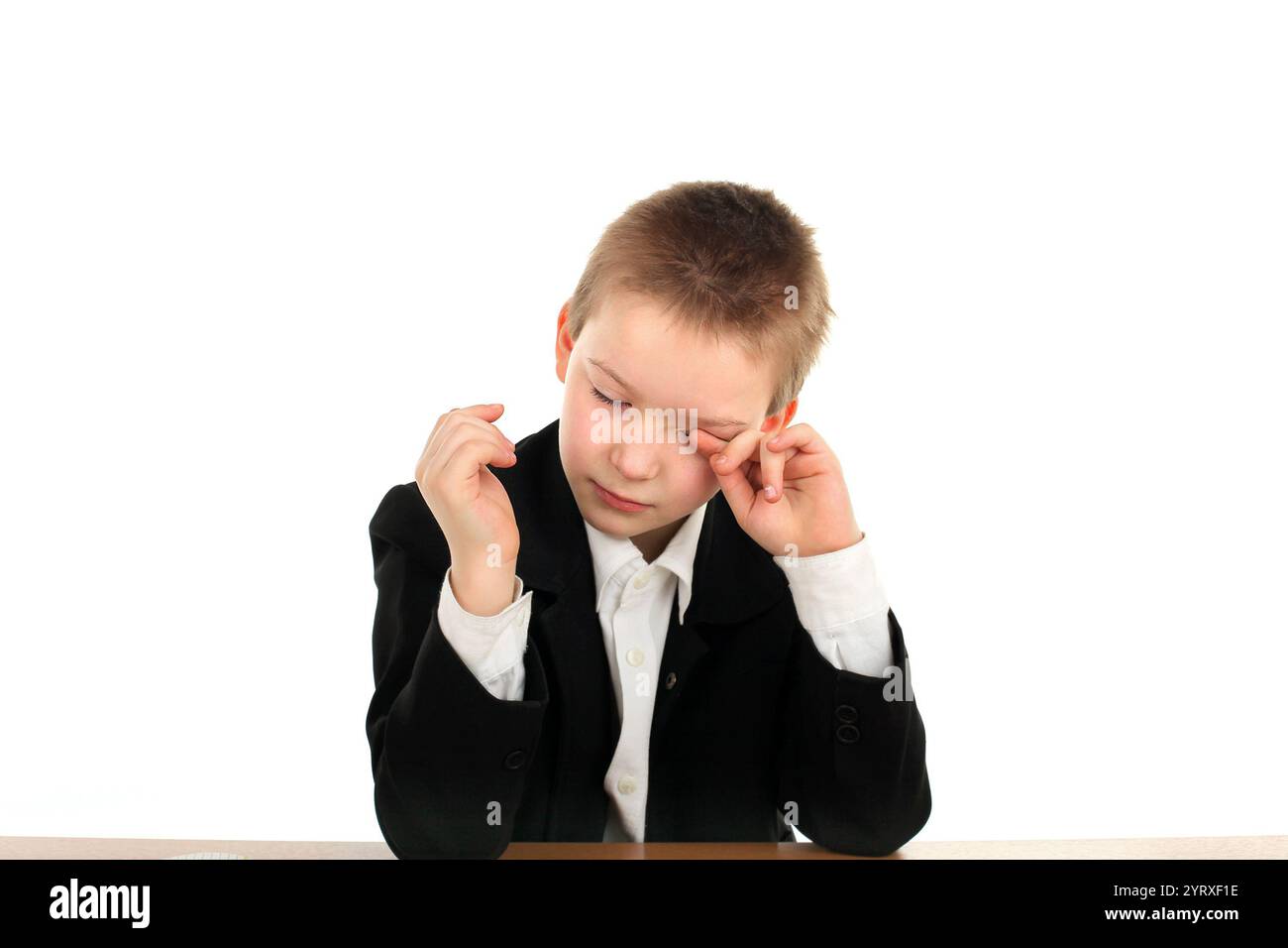 very sad schoolboy crying on the table isolated on the white background ...