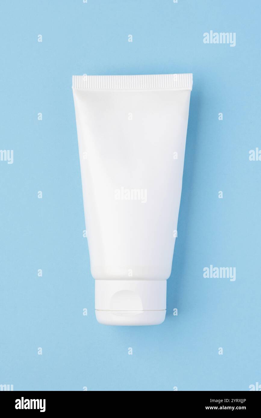 A white cosmetic tube on a pastel blue background. Ideal for mockups ...