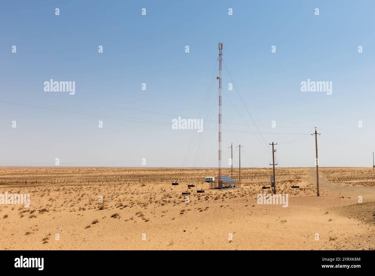 A cell tower equipped with solar panels stands alone in the arid desert ...