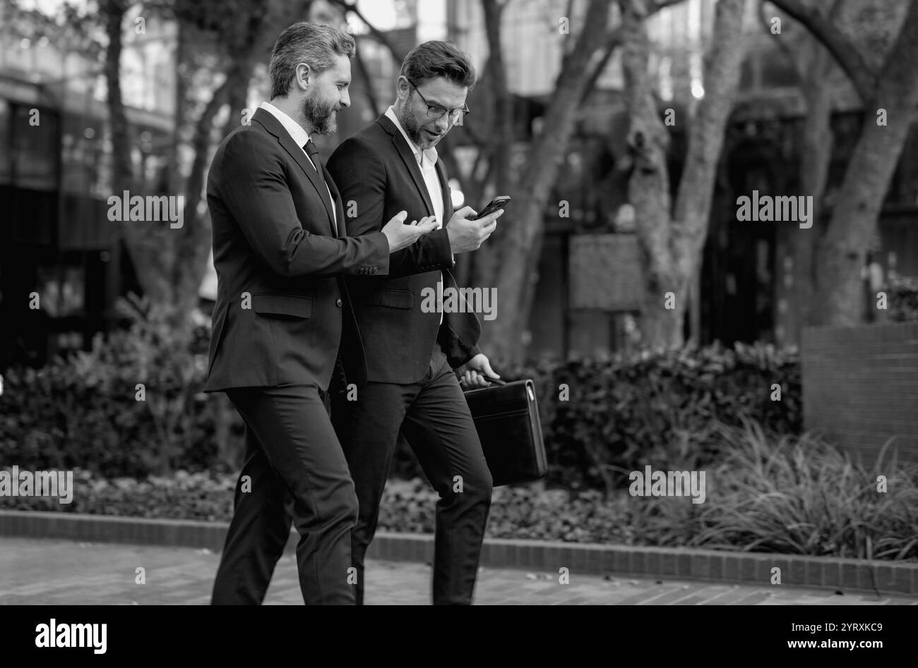 Businessmen walk in the street. Two businessmen walking and talking at ...