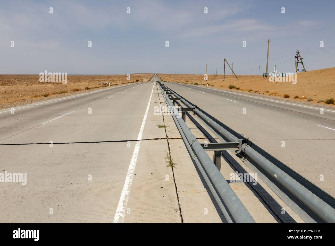 A long straight concrete road cuts through the arid desert of ...