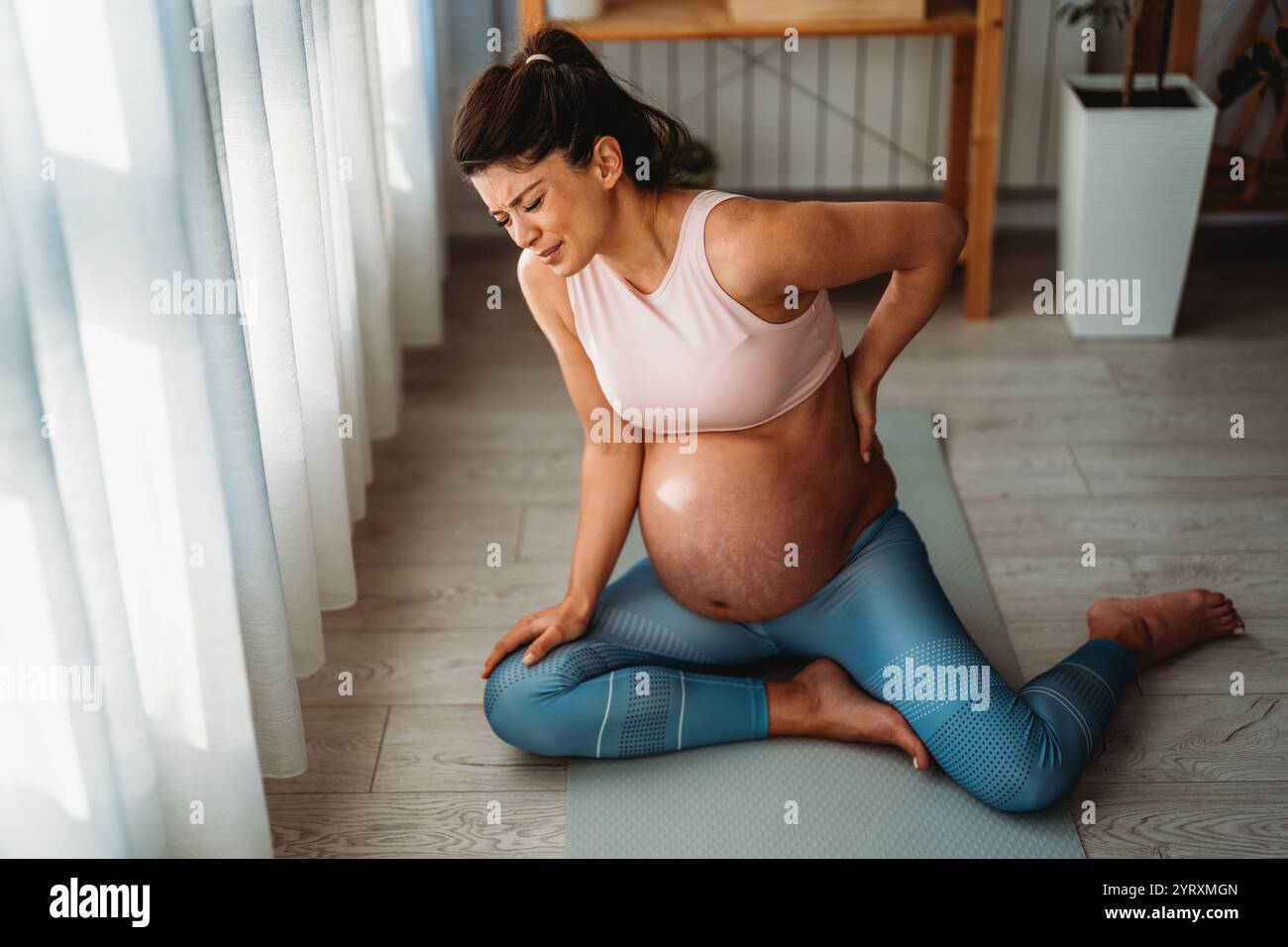 Young mother suffering from lumbago during pregnancy. Pregnant woman feeling pain in her lower ...