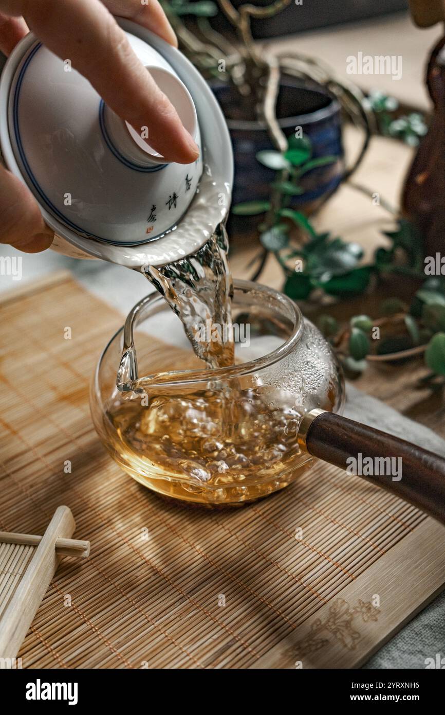 Pouring aromatic tea into a beautiful teapot surrounded by greenery ...