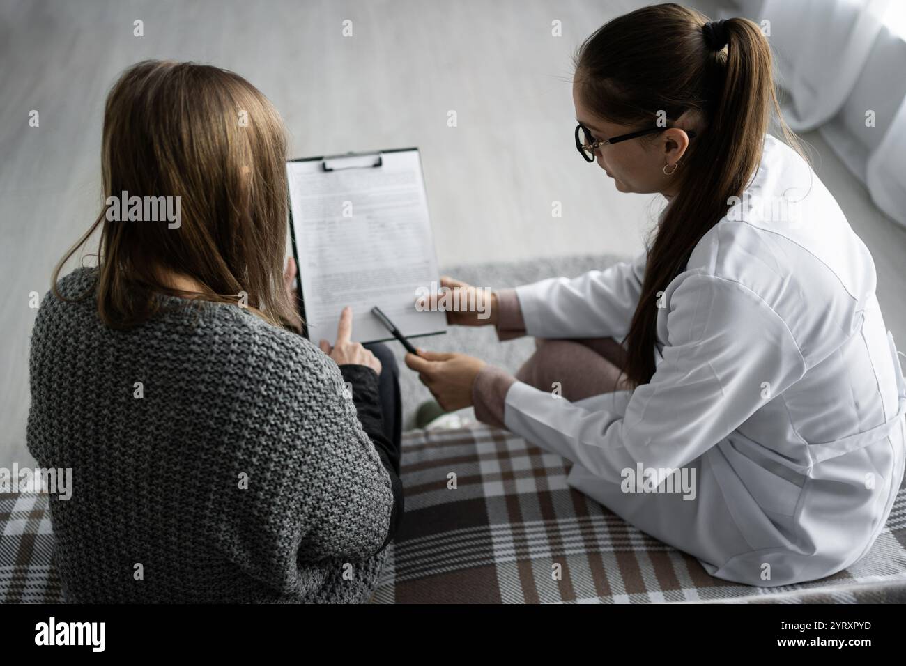 female doctor consulting senior patient give her form at consultation. Physician talking to ...