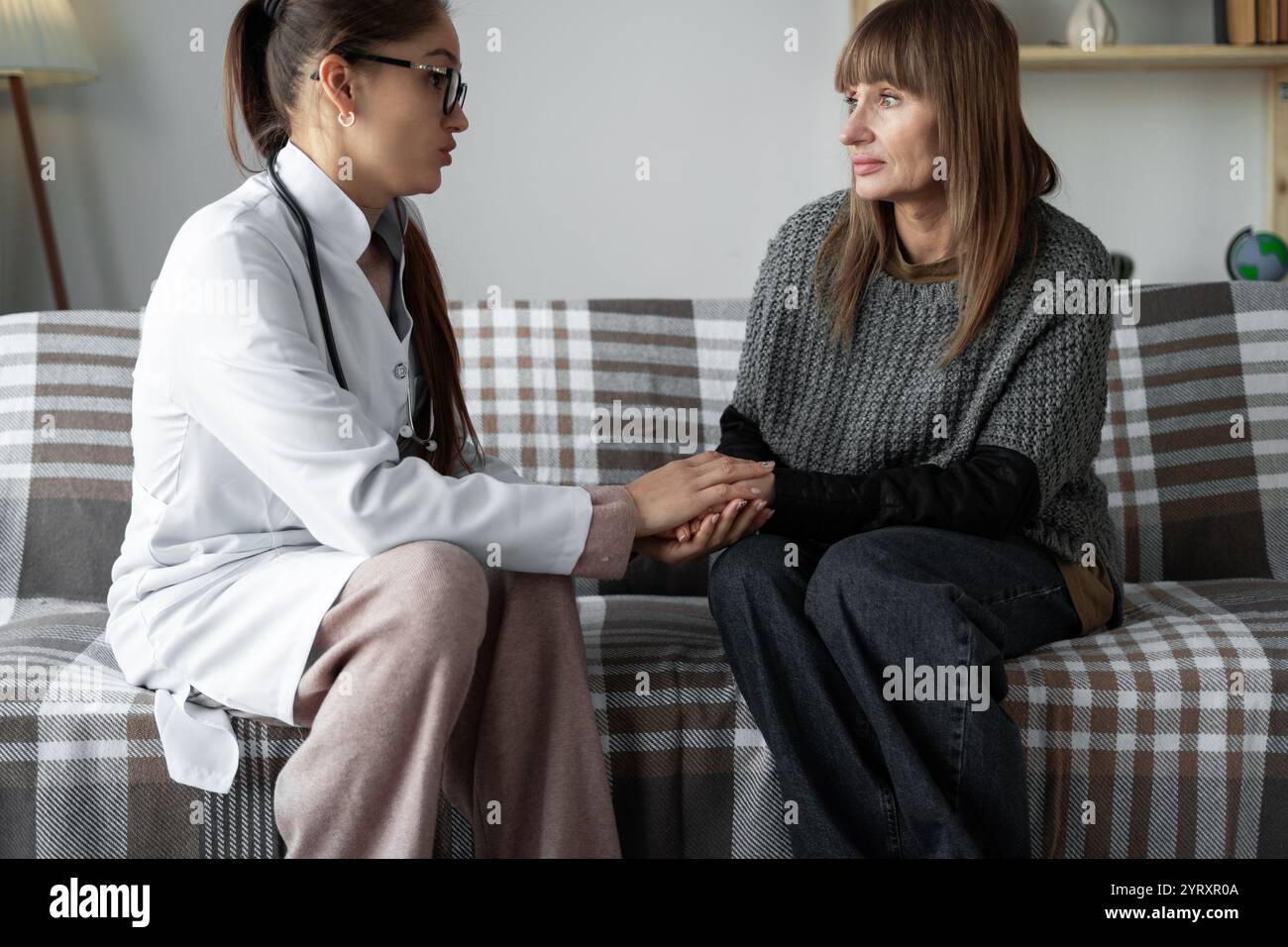 Female physician talking with elderly lady patient holding her hand in ...