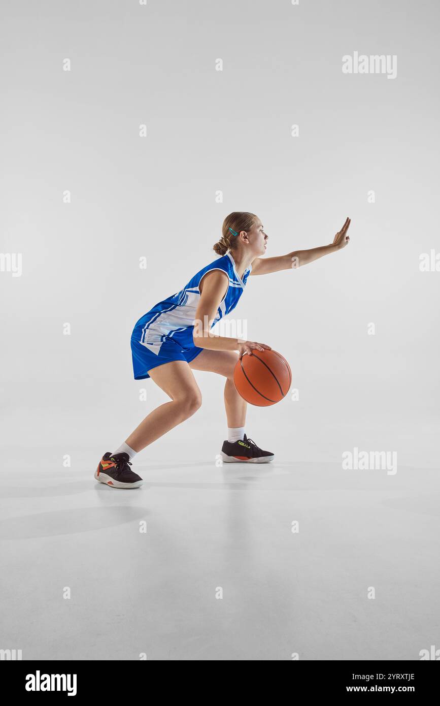 Competitive young girl, basketball player in blue uniform in motion ...
