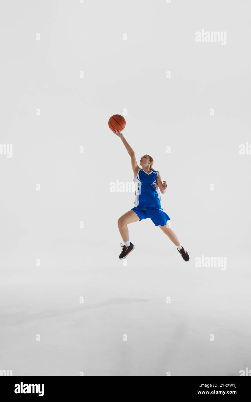 Slam dunk. Full-length vertical image of young teen girl in blue ...