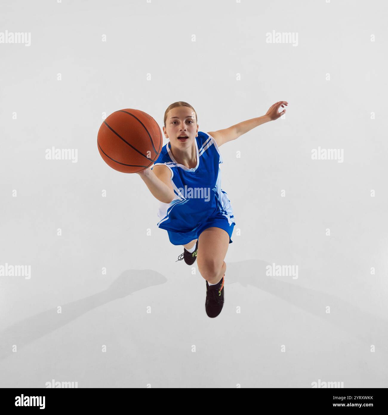 Slam dunk. Top view dynamic image of young focused teen girl in blue ...