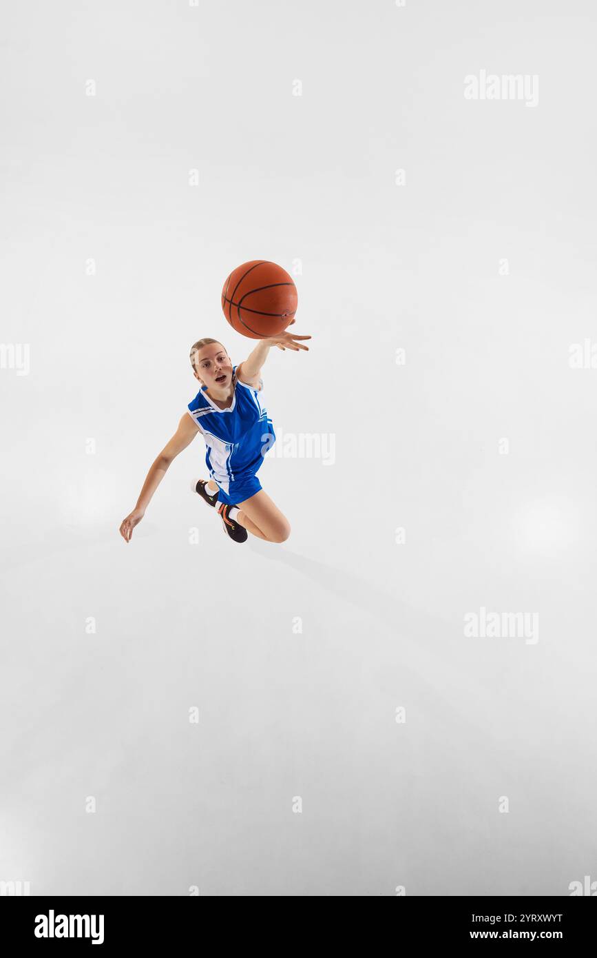 Slam dunk. Top view dynamic image of young focused teen girl in blue ...