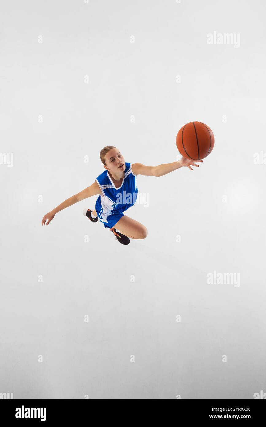Slam dunk. Top view dynamic image of young focused teen girl in blue ...