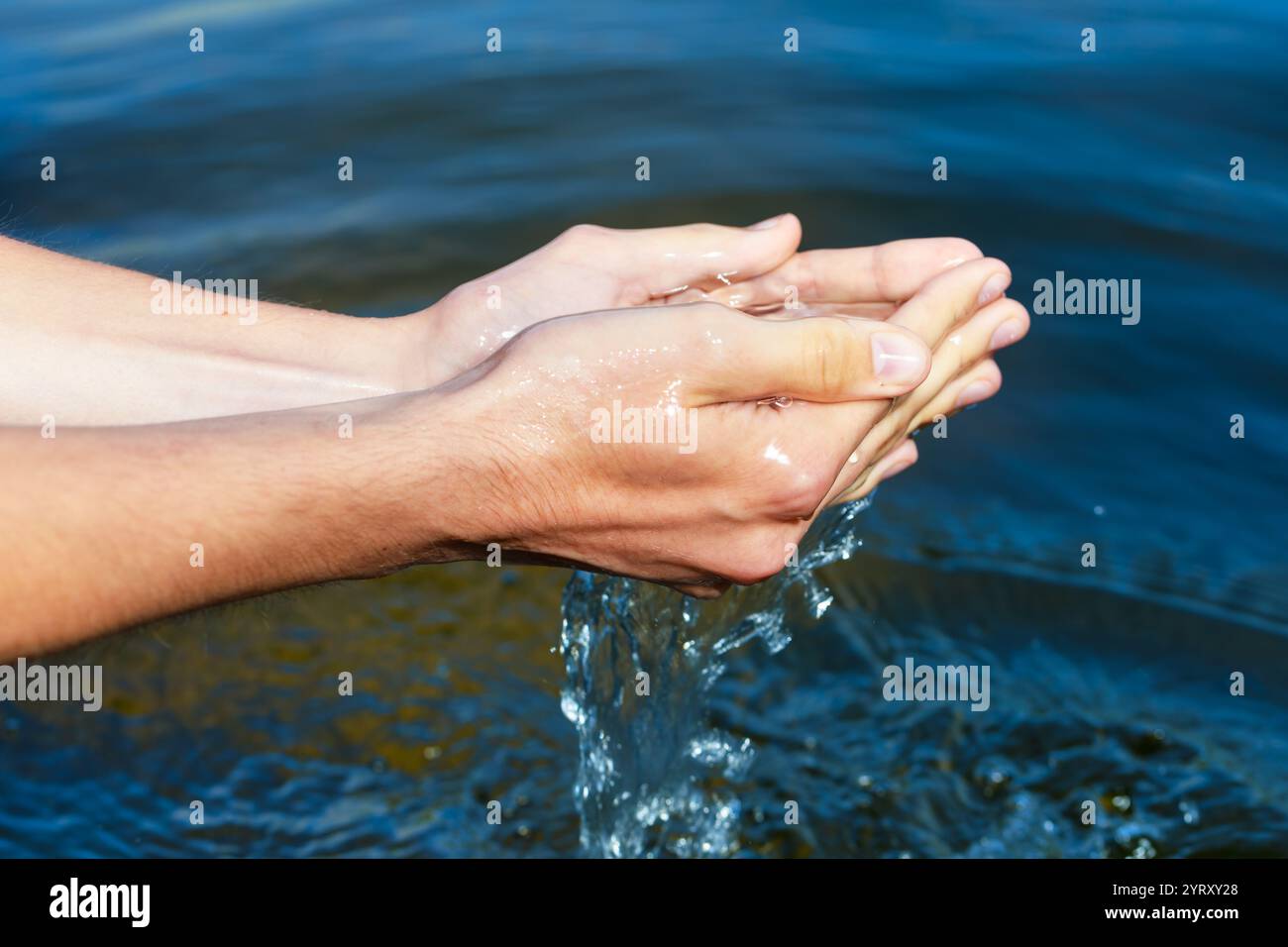 Individual collecting raw water from a tranquil lake using hands ...