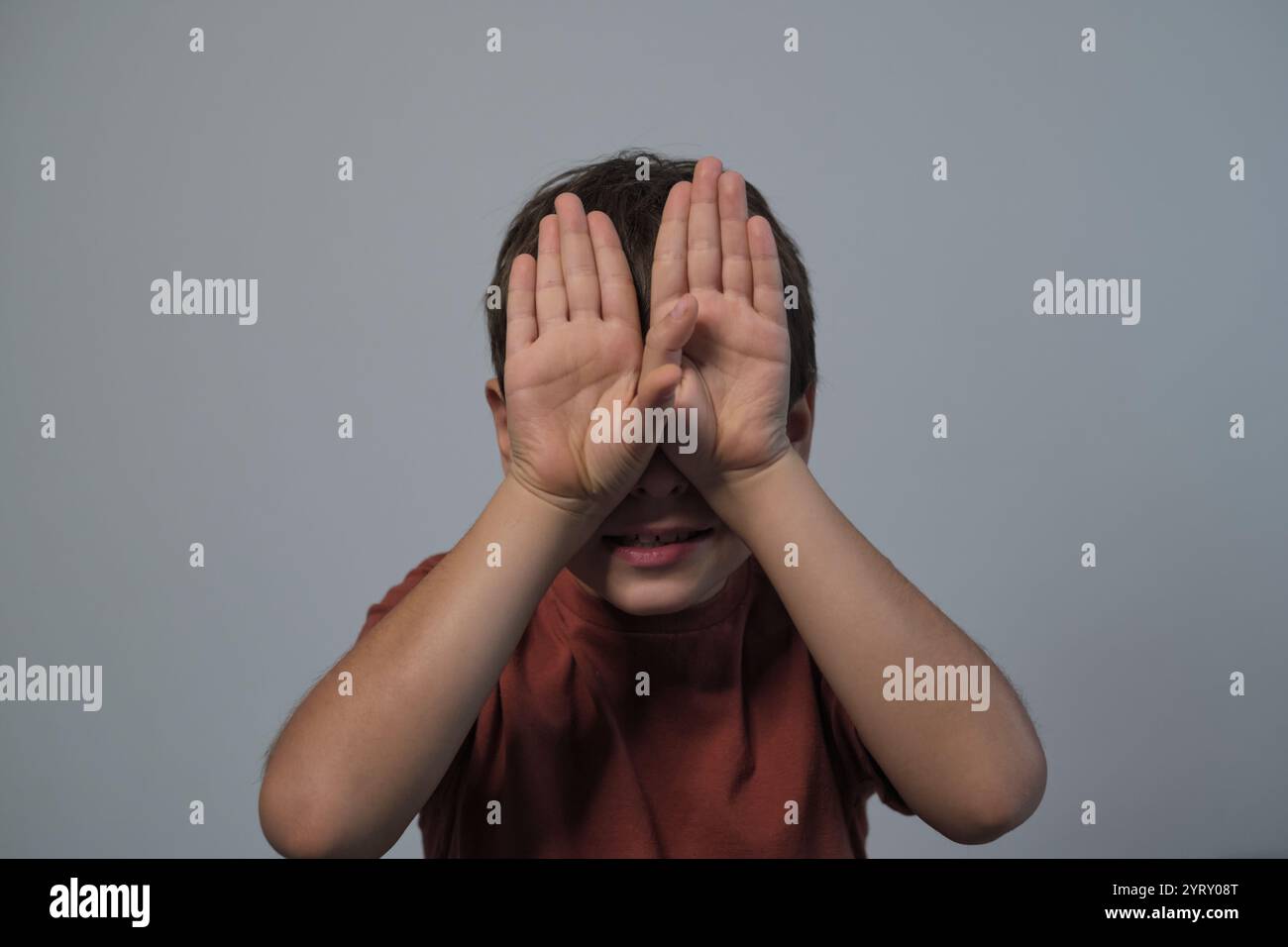 Child with hands cupped around eyes, giggling, pretending to be a ...