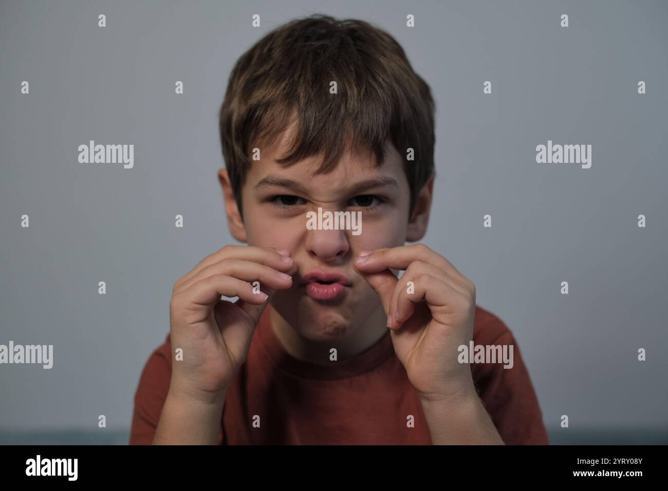 Child playfully making a face, fingers spread like paws. Demonstrates ...
