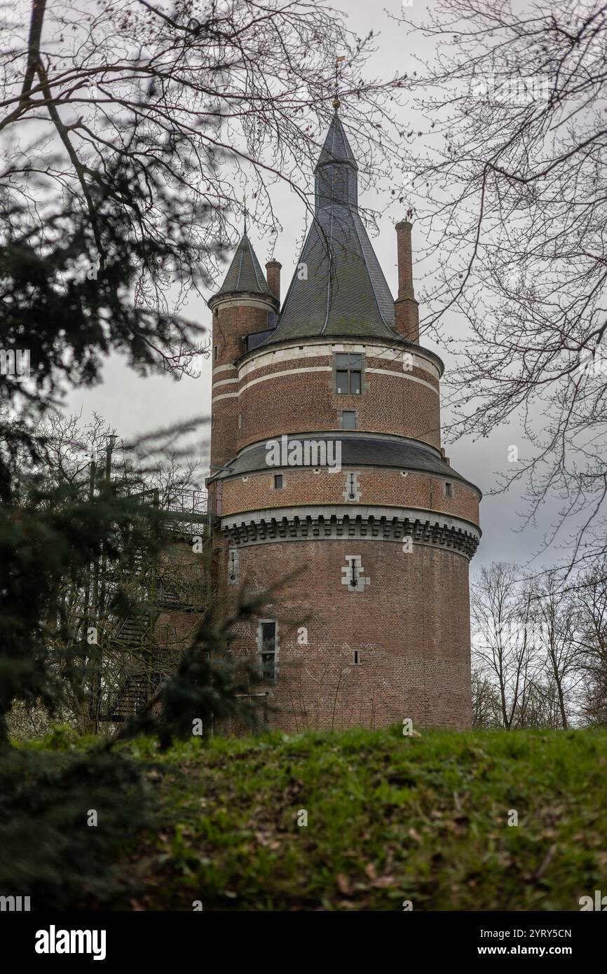 A historic brick castle with tall spire-like towers reflected in a calm ...