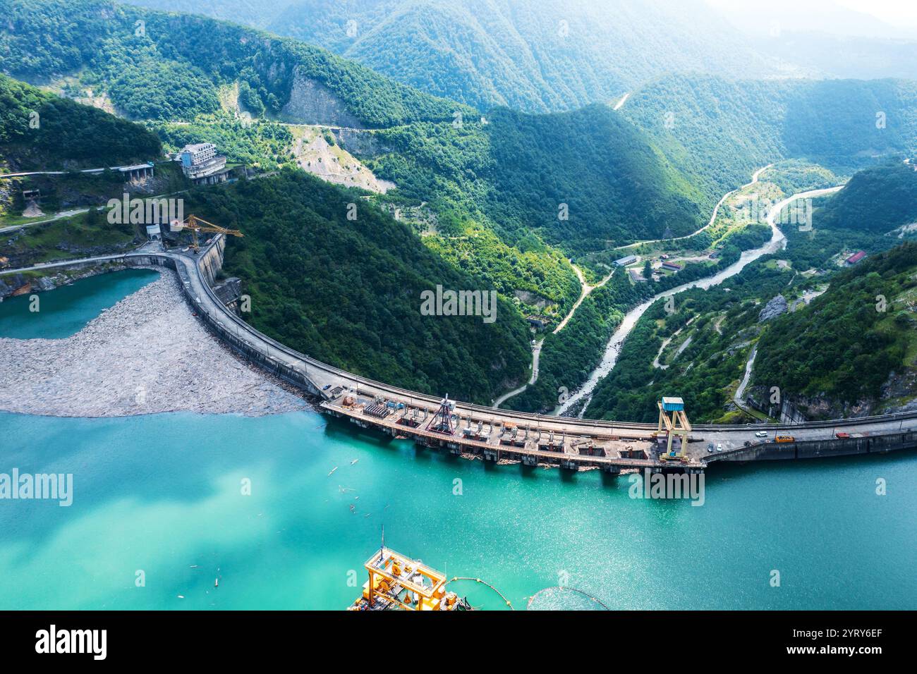 Large hydroelectric dam with turquoise reservoir surrounded by lush ...