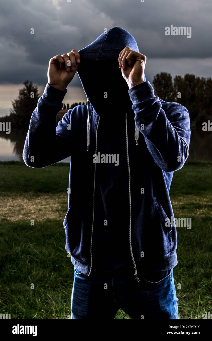 Mysterious hooded man covering his face with a hoodie in a dramatic ...
