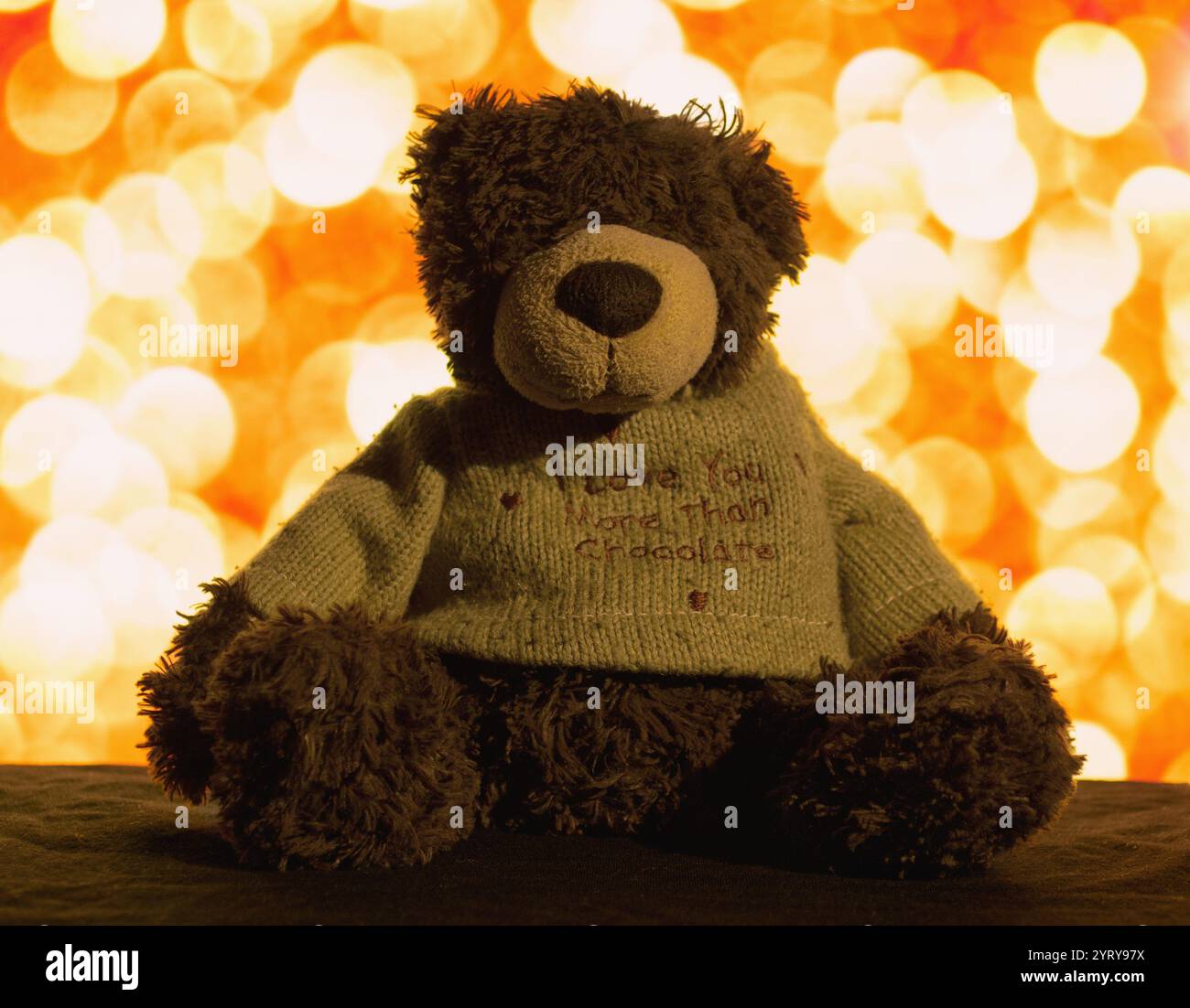 Cute teddy bear sitting on the background of orange lights Stock Photo ...