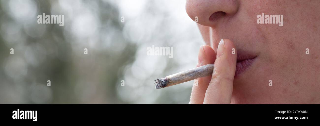 Woman smoking a marijuana cigarette outdoors, close-up view of her ...