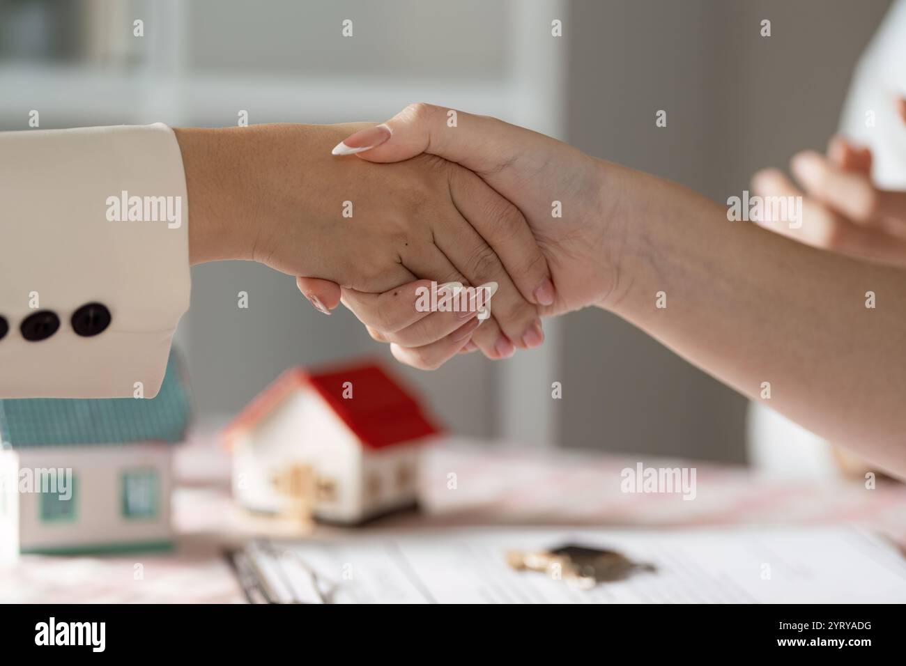 Real Estate Agent Shaking Hands with Client Over Contract and Model ...