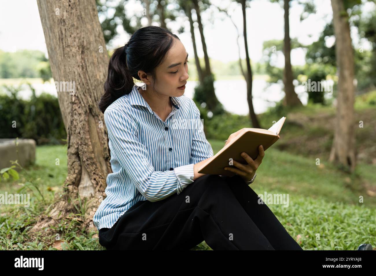 Young Professional Reading and Working Outdoors in a Serene Park ...