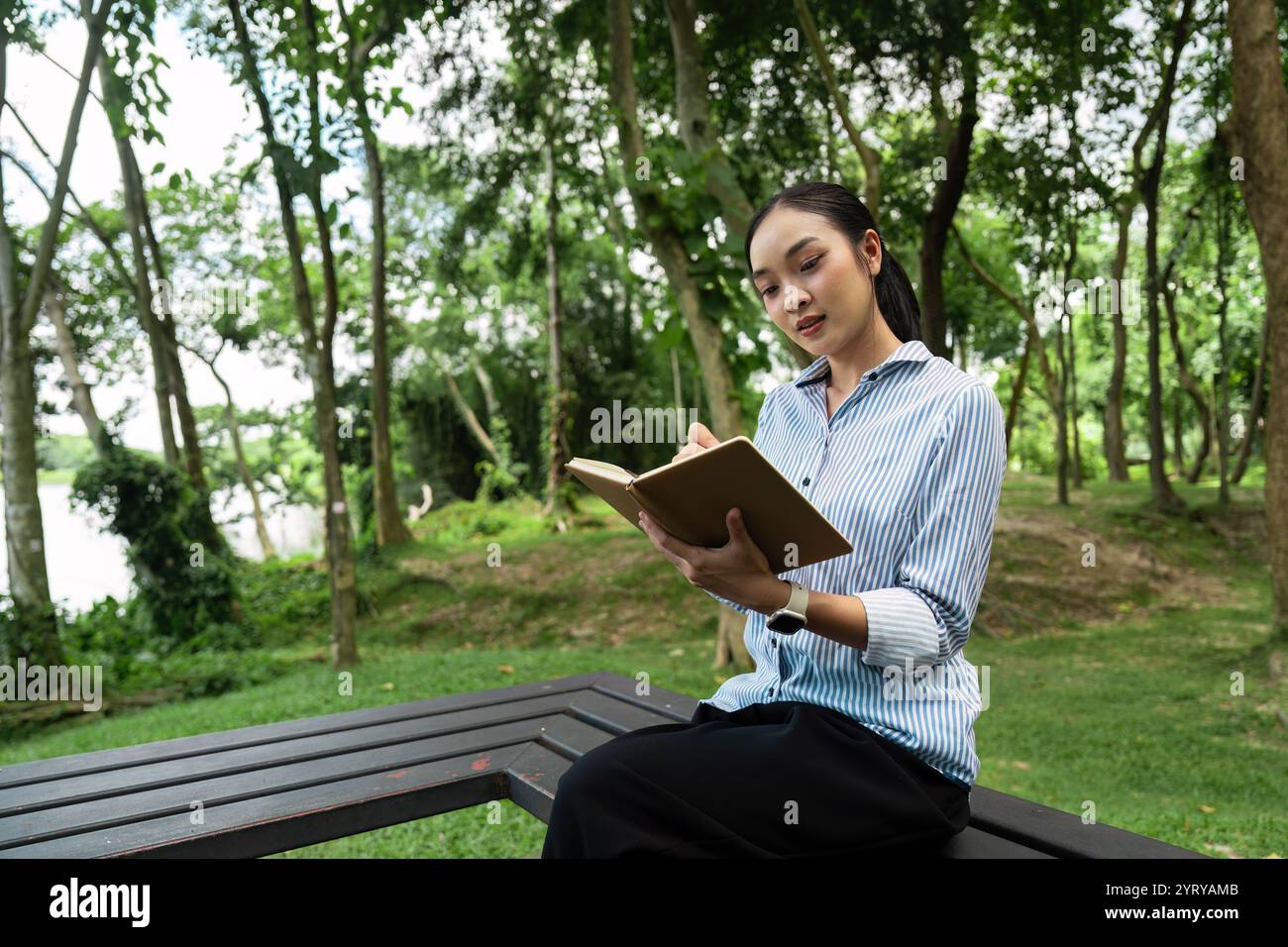 Young Professional Reading and Working Outdoors in a Serene Park ...