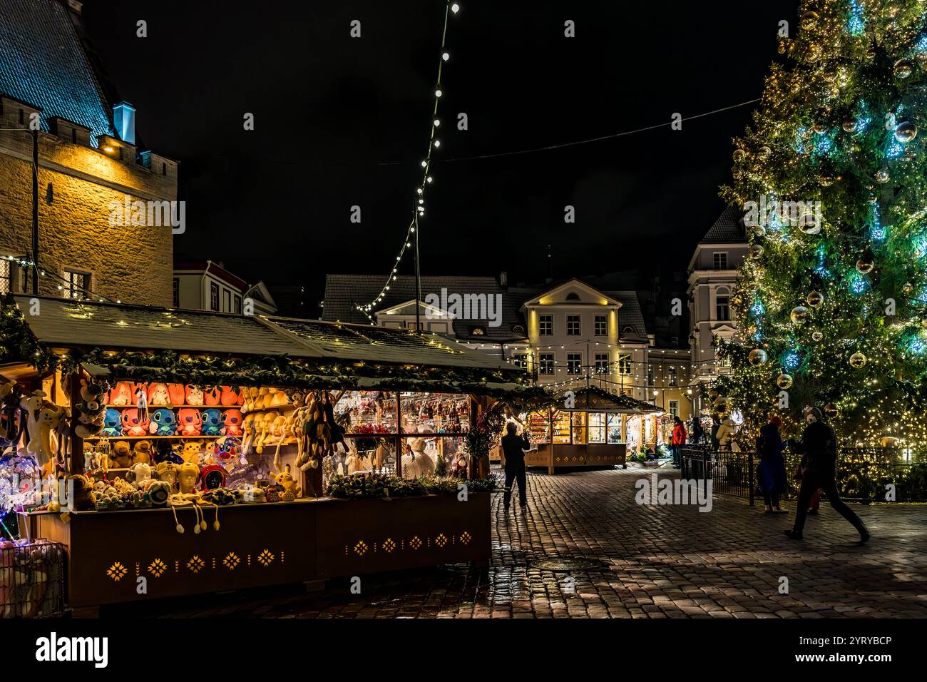 Christmas market stalls illuminated at night with decorated tree in ...