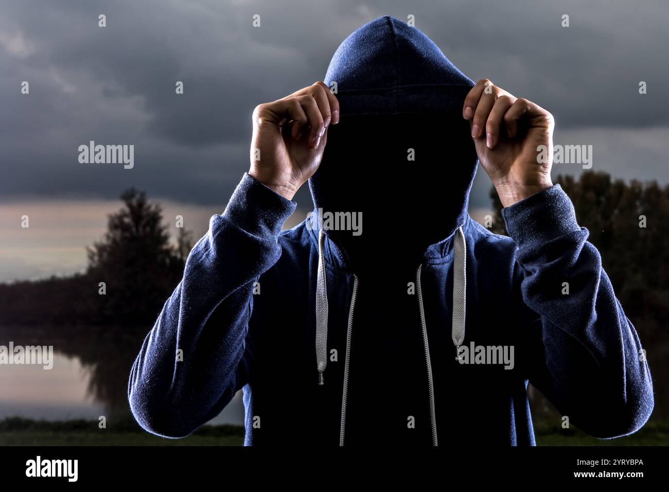 Mysterious man covering face with hood in dramatic landscape Stock ...