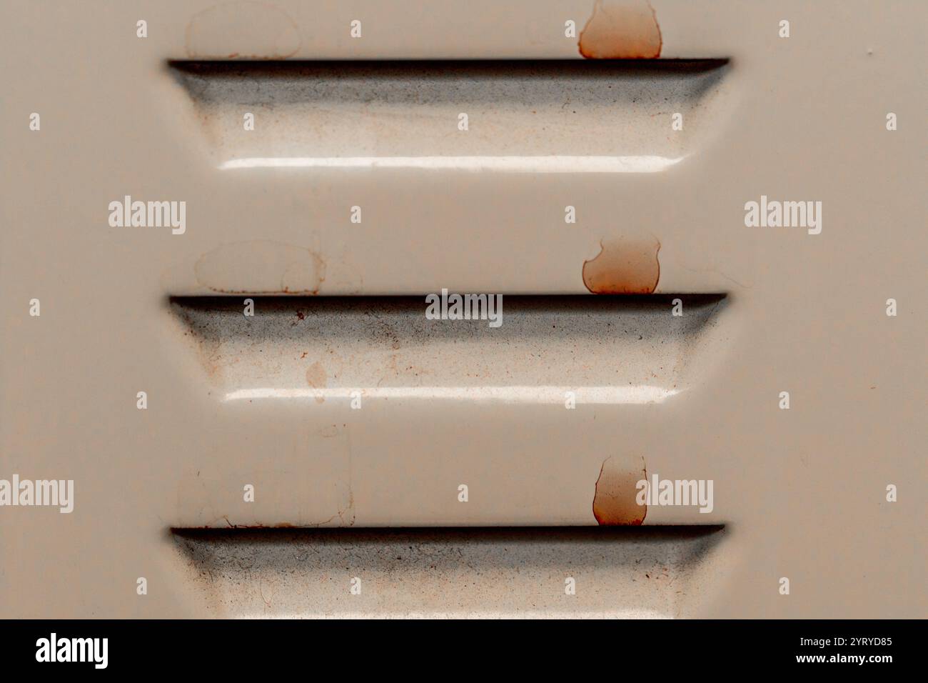 Rust stains are developing on a beige metal ventilation grill ...