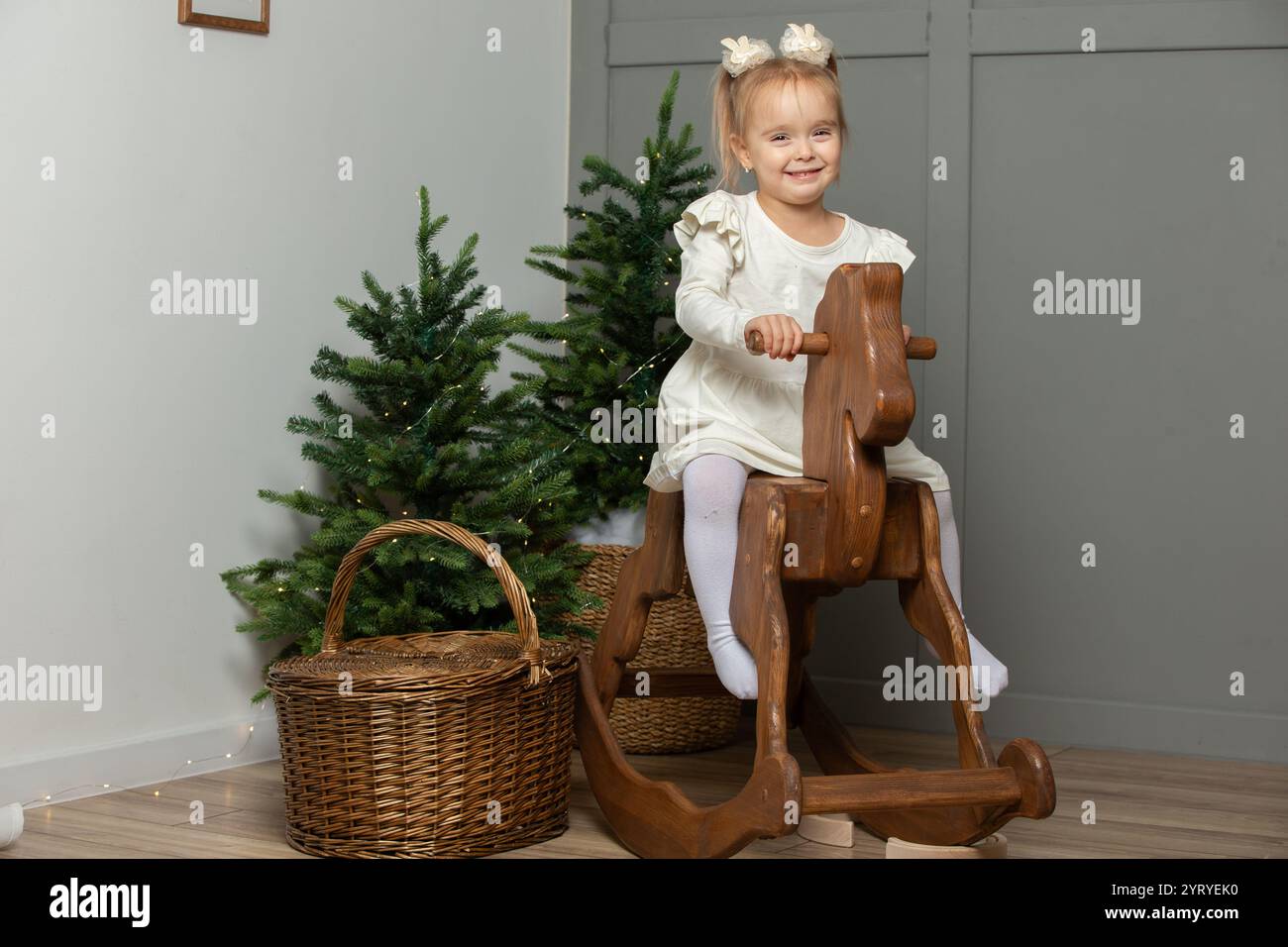 Happy little girl rides on a wooden horse gurney in the Christmas room ...