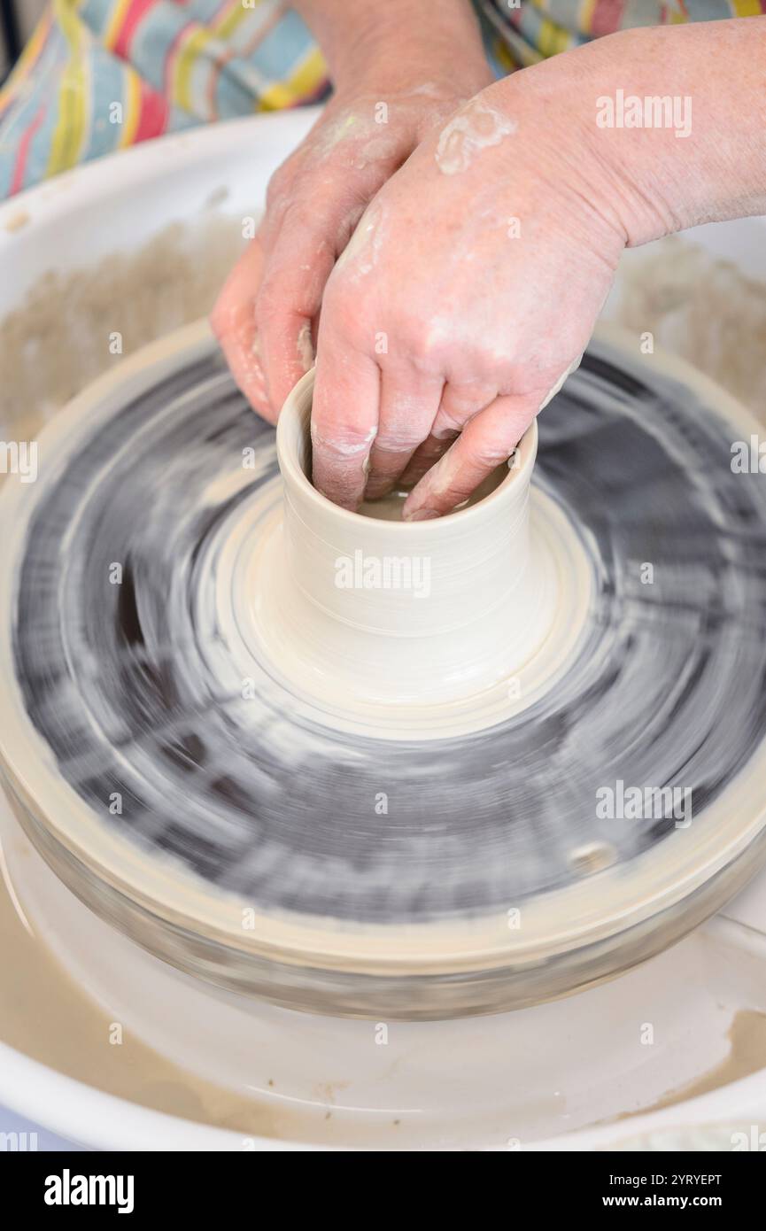 Hands shaping clay on a pottery wheel, highlighting traditional craftsmanship, ceramic art, and ...
