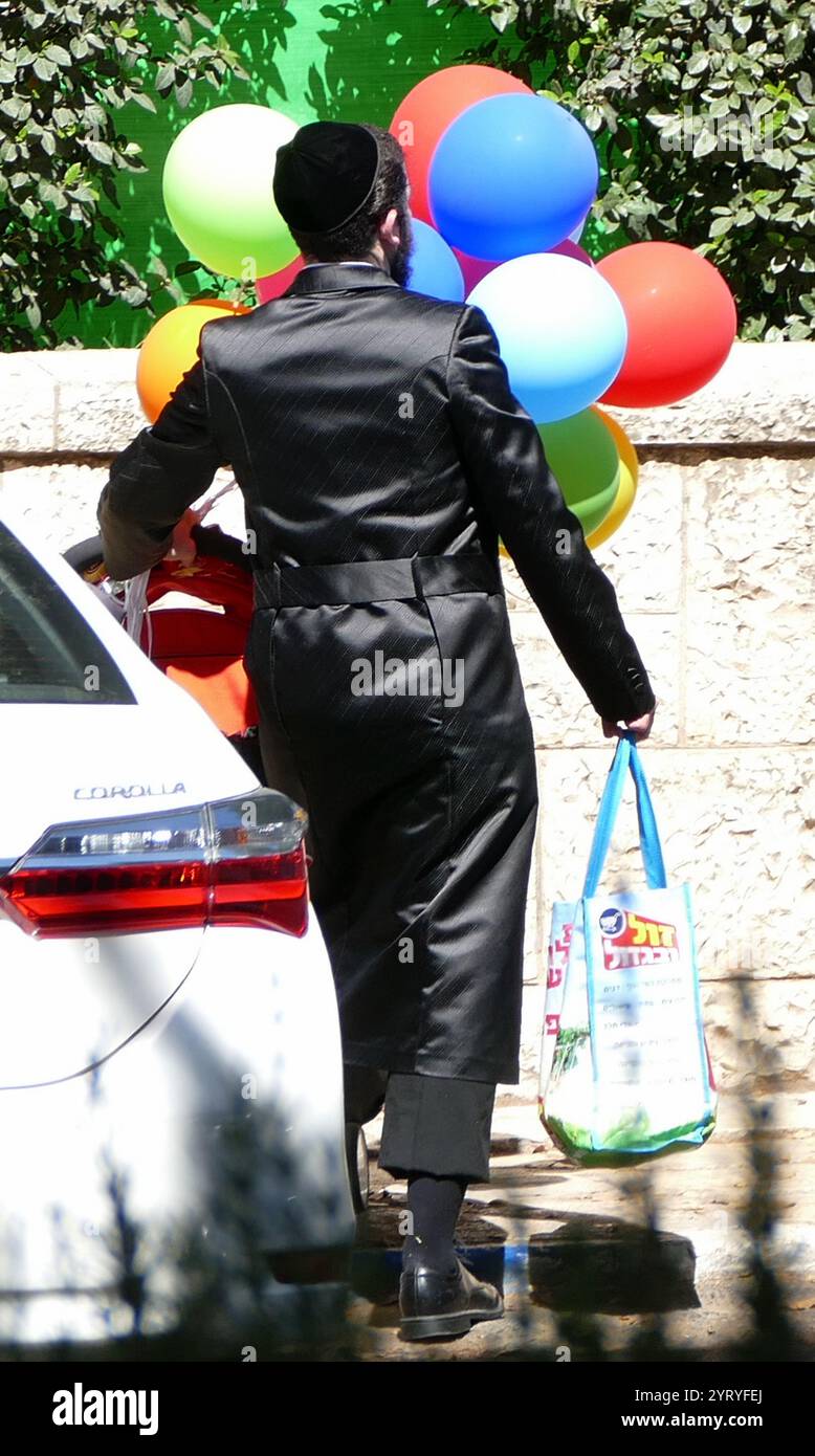 Hassidic Jewish father with balloons on his way to a child's party ...