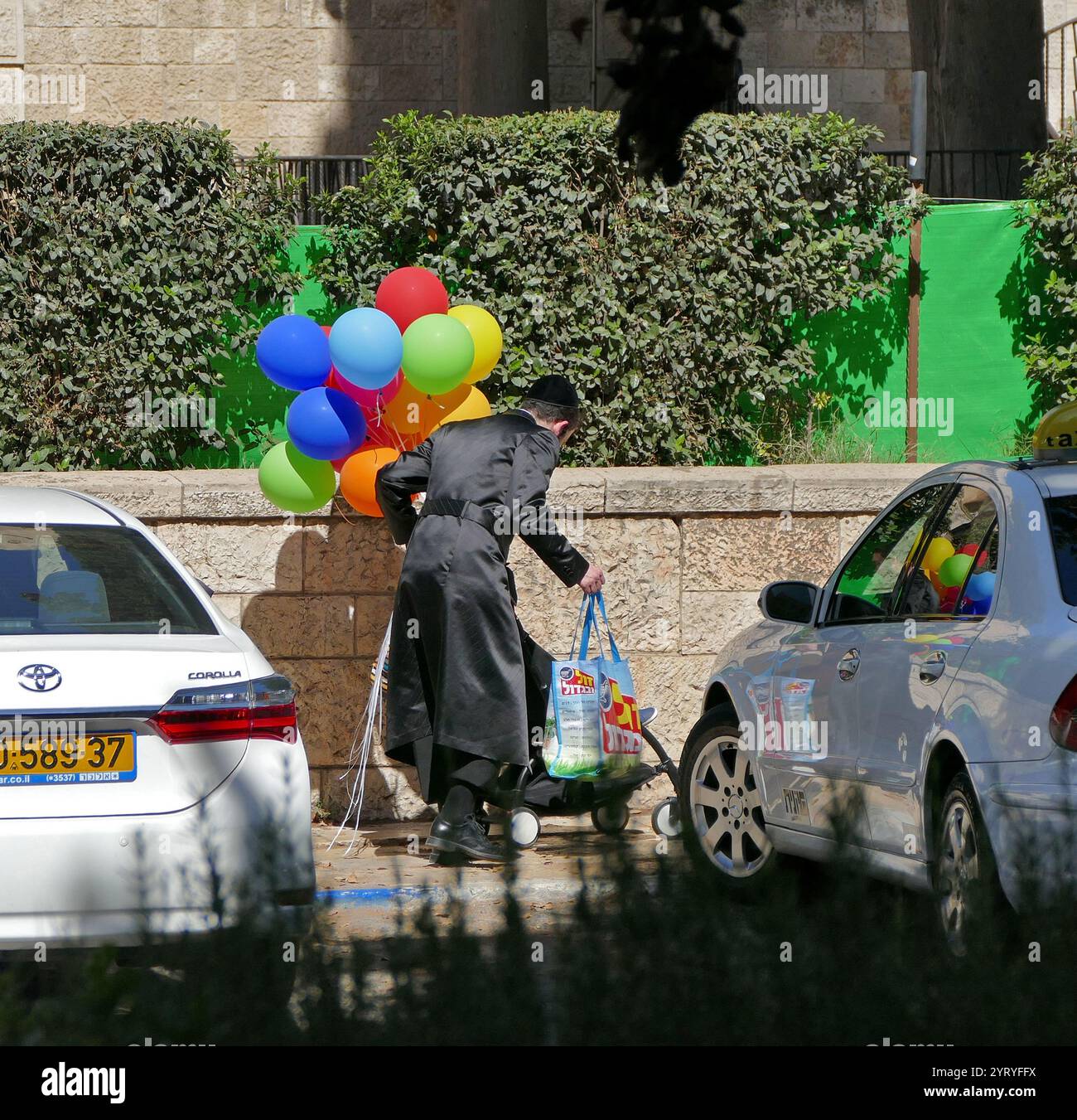 Hassidic Jewish father with balloons on his way to a child's party ...