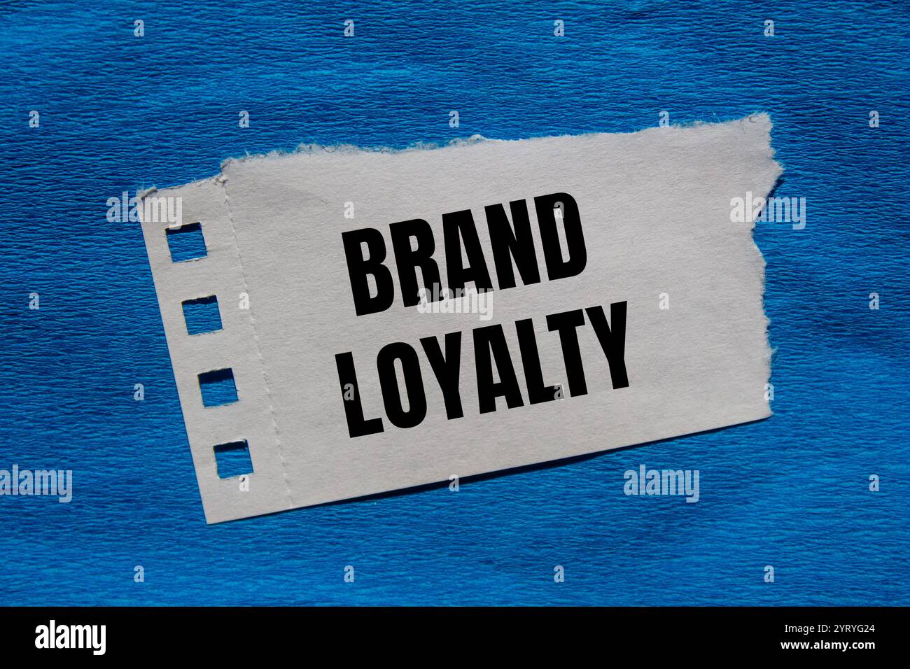 Brand loyalty message written on ripped torn paper piece with blue ...