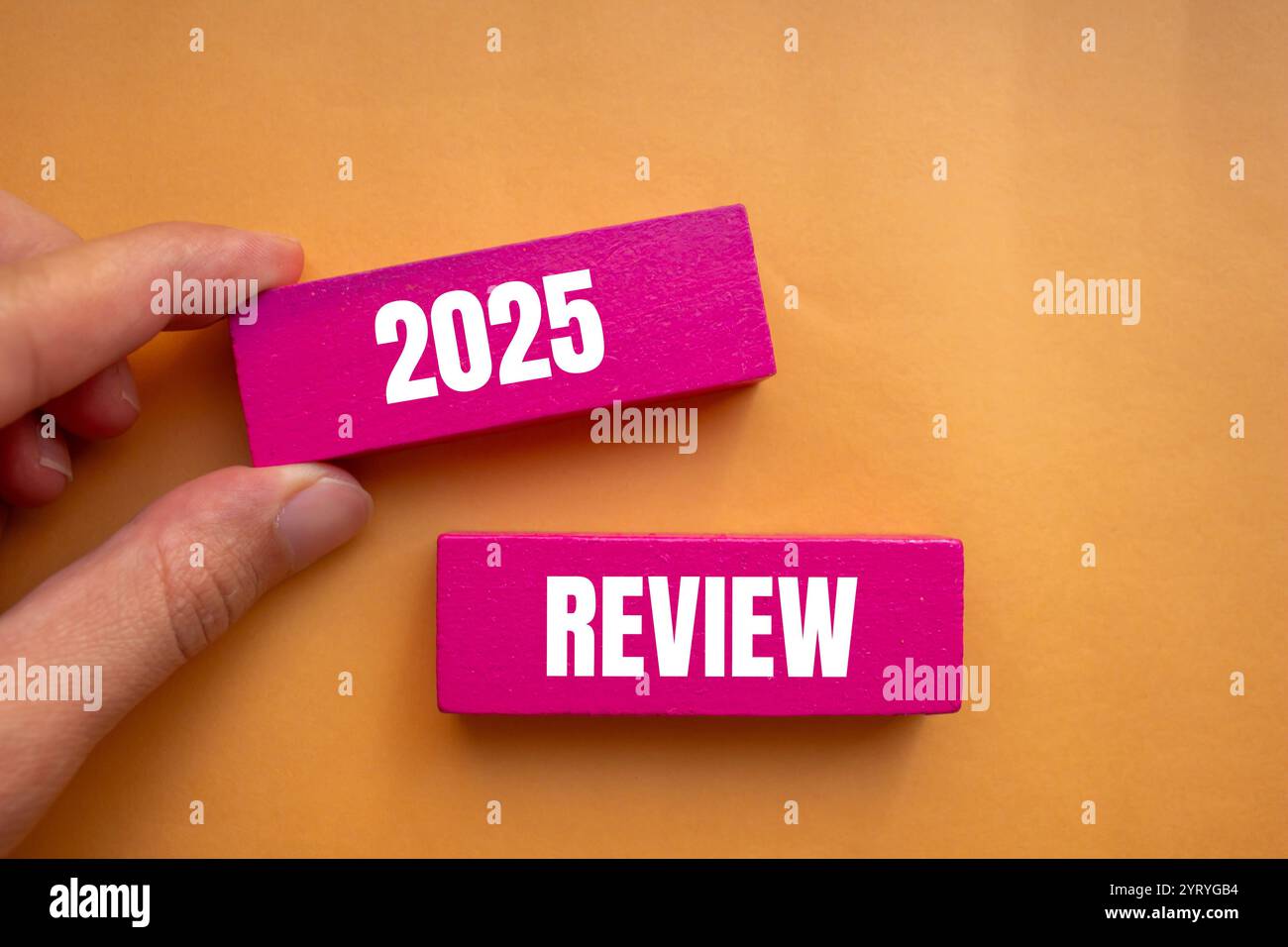 2025 review message written on pink wooden blocks with orange background. Conceptual 2025 review ...