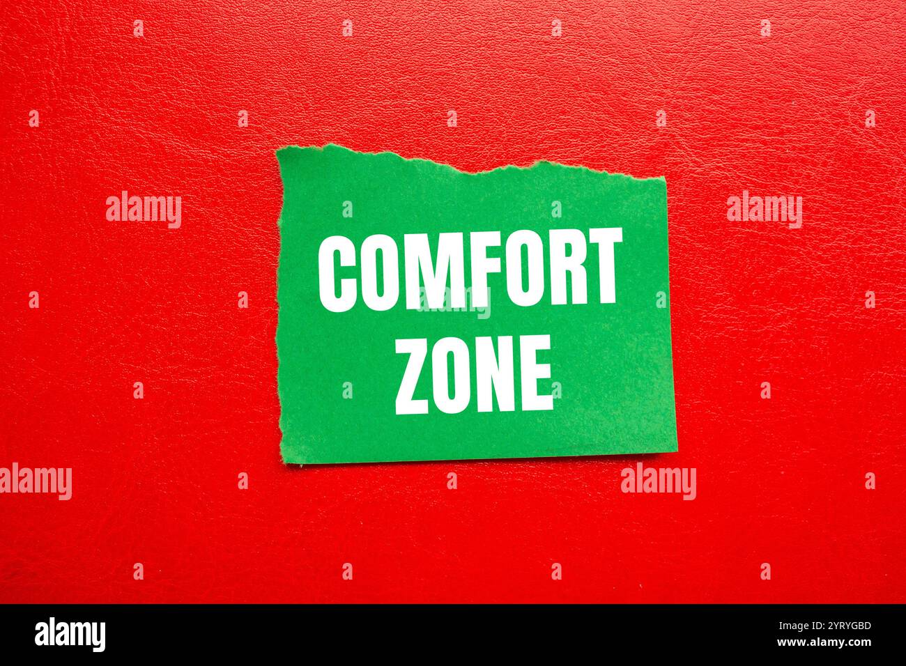 Comfort zone message written on ripped torn green paper piece with red background. Conceptual ...