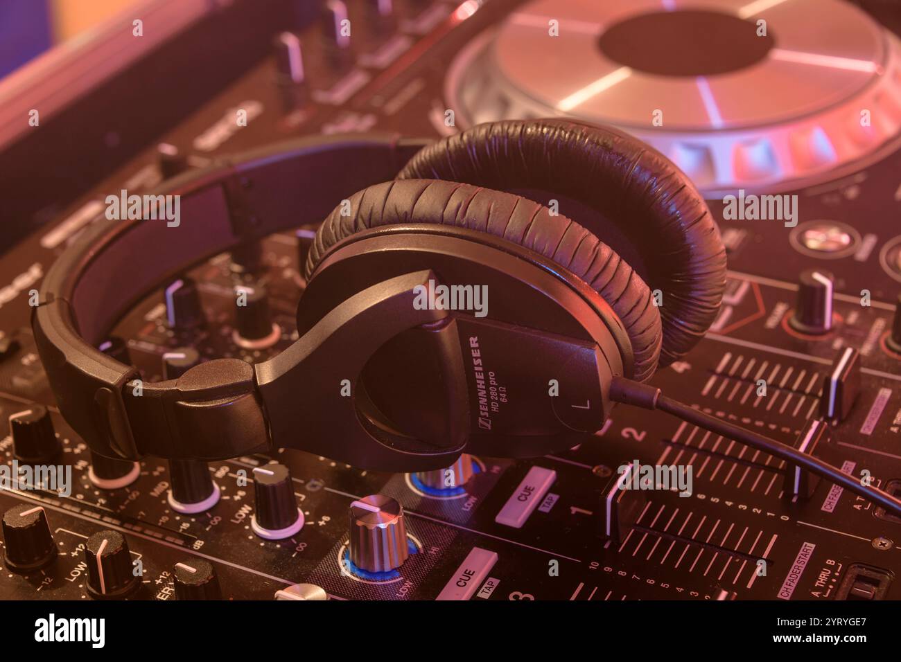 Headphones resting on a DJ mixing console in warm stage lighting ...