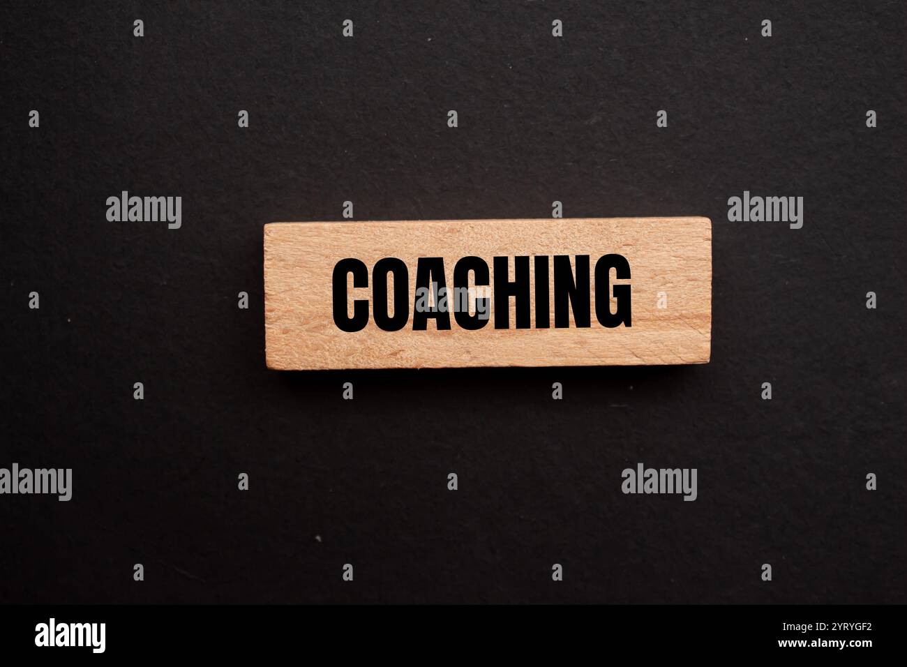 Coaching message written on wooden block with black background ...