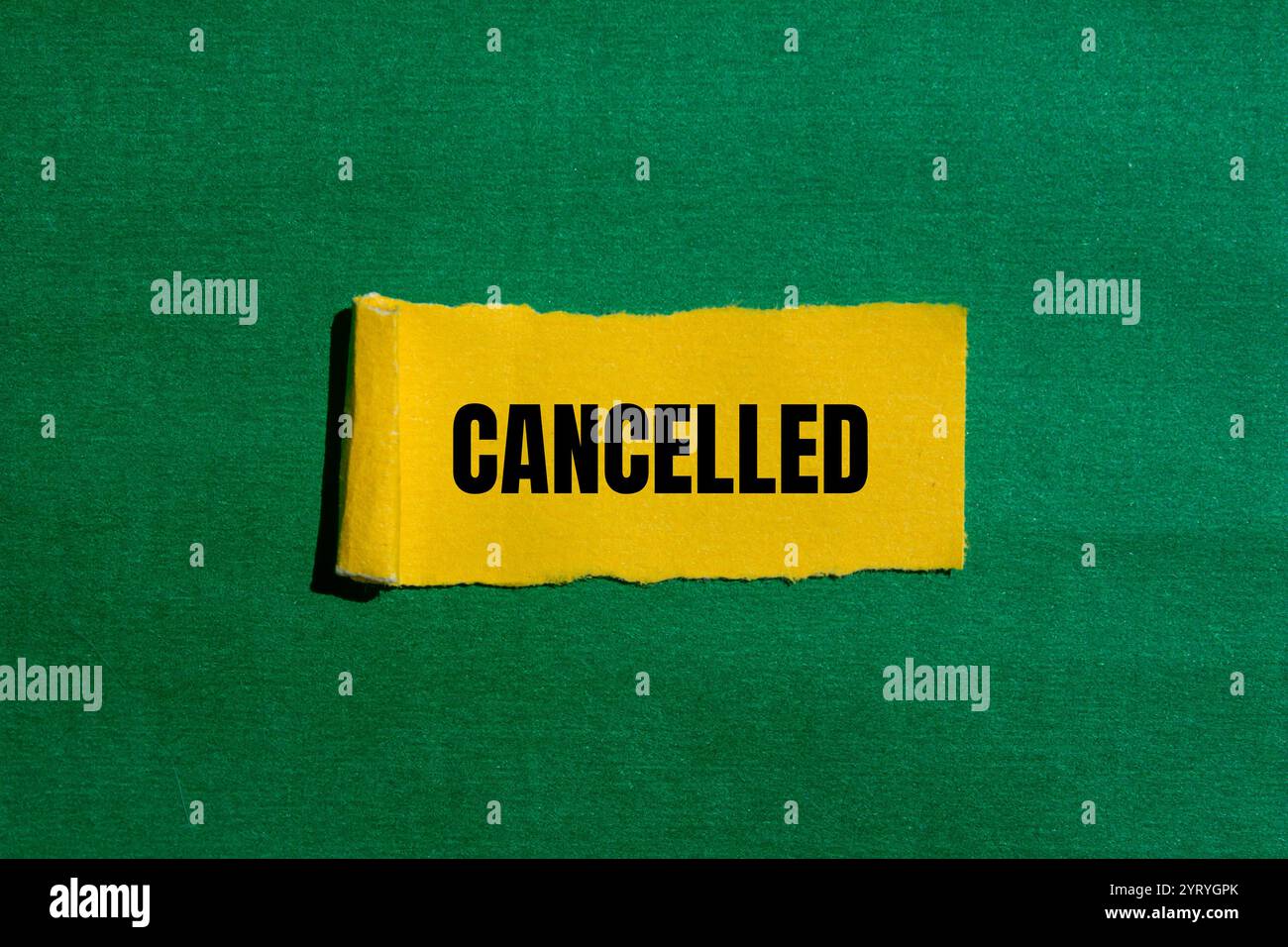 Cancelled message written on ripped torn yellow paper piece with green ...