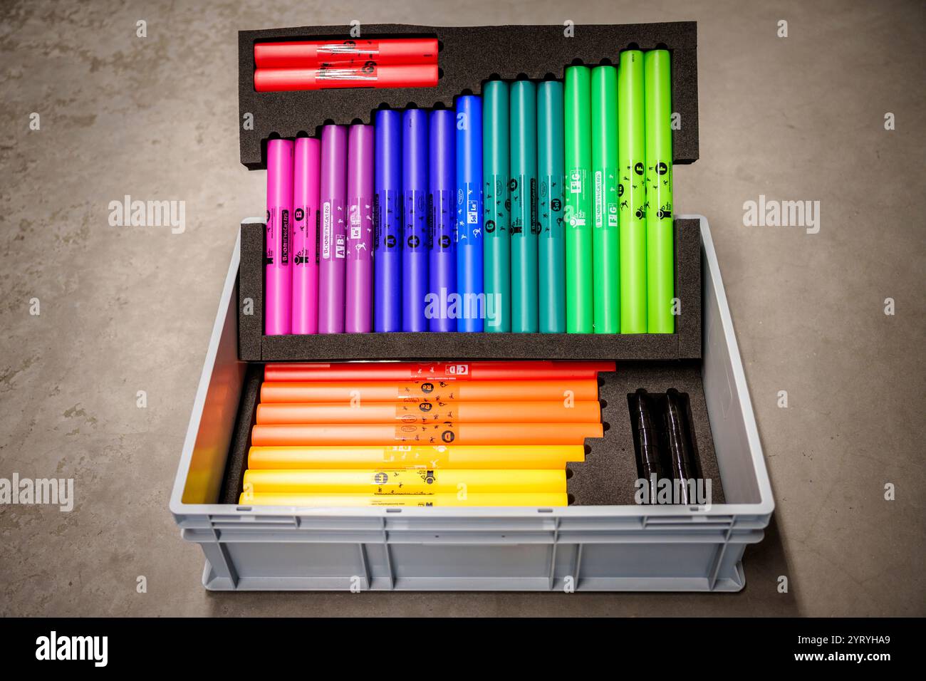 Hands organizing colorful percussion tubes (Boomwhackers) in protective ...