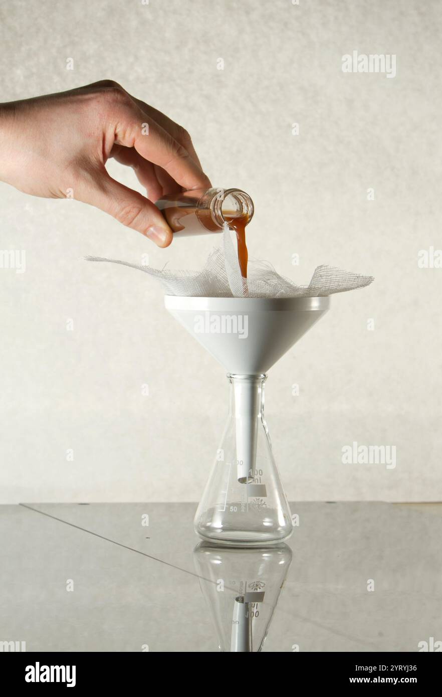 Close-up of scientist pouring brown chemical liquid into filtering ...