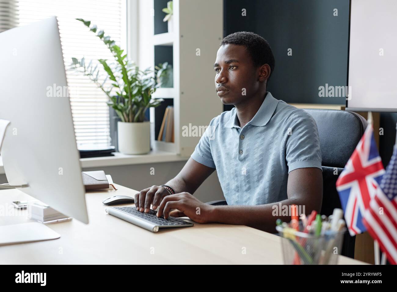 Medium shot of young African American teacher typing on computer ...