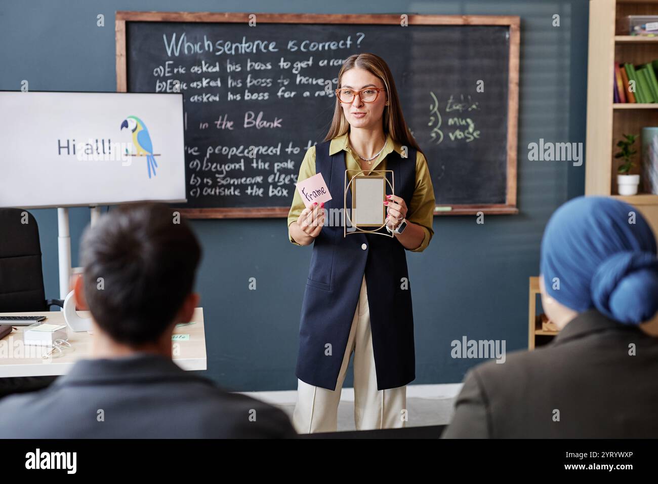 Medium full shot of young female English language instructor talking to ...