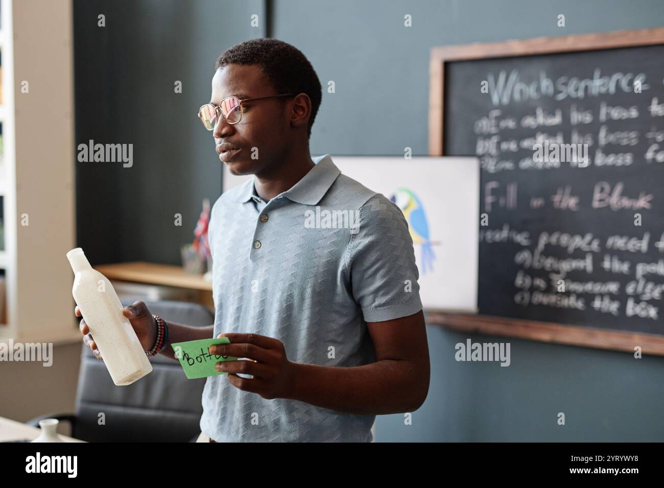 Medium shot of young African American teacher holding bottle and sticky ...